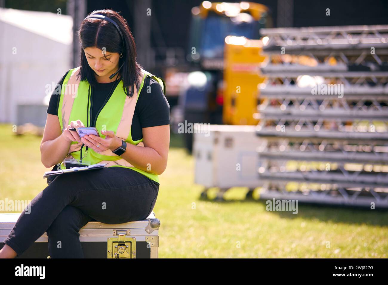 Female Production Worker With Mobile Phone Setting Up Outdoor Stage For ...