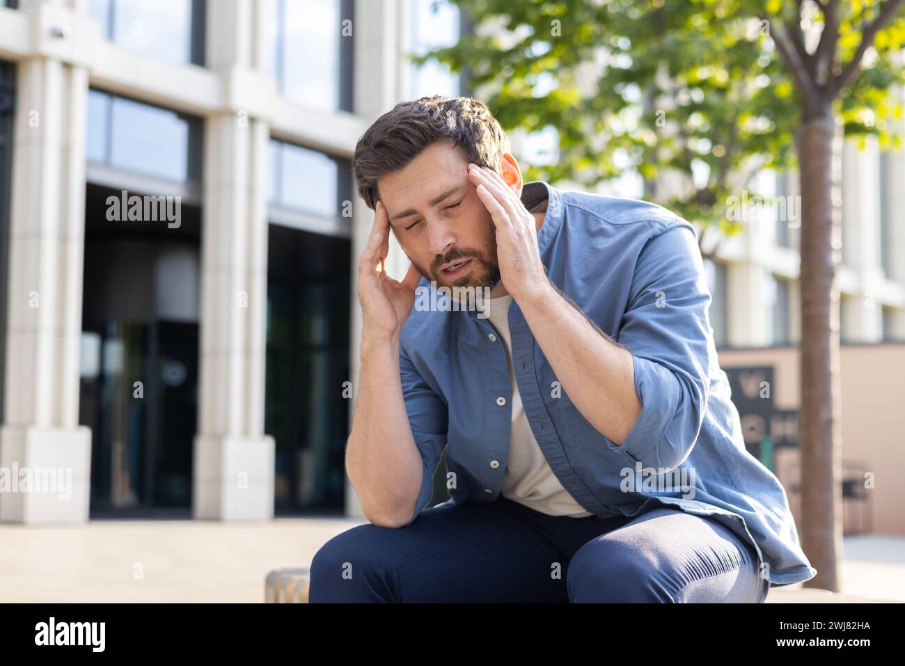 Distressed mature businessman rubbing temples due to headache, sitting ...