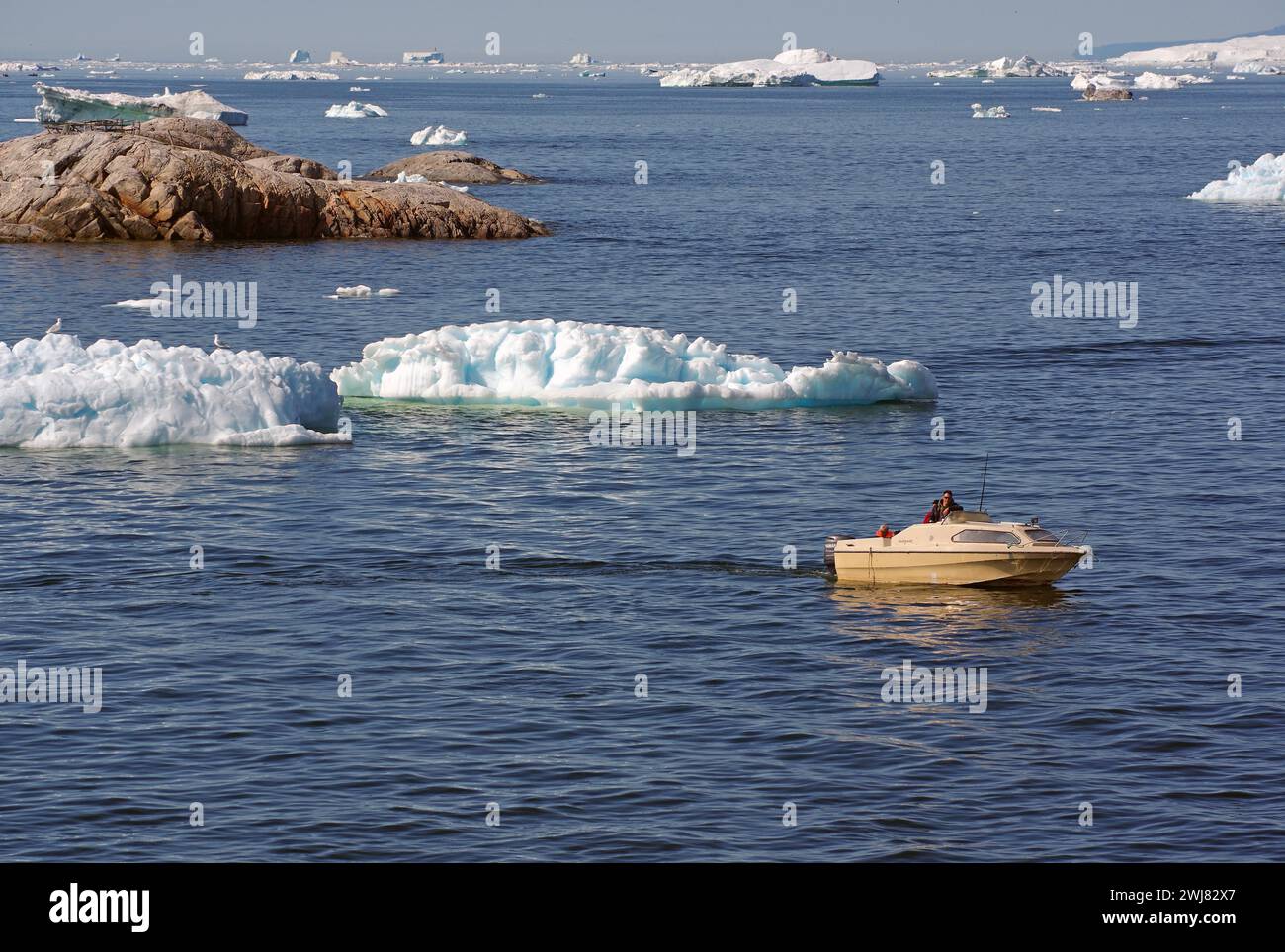 Small boat between icebergs and rocks, Ilulissat, Disko Bay, Denmark ...