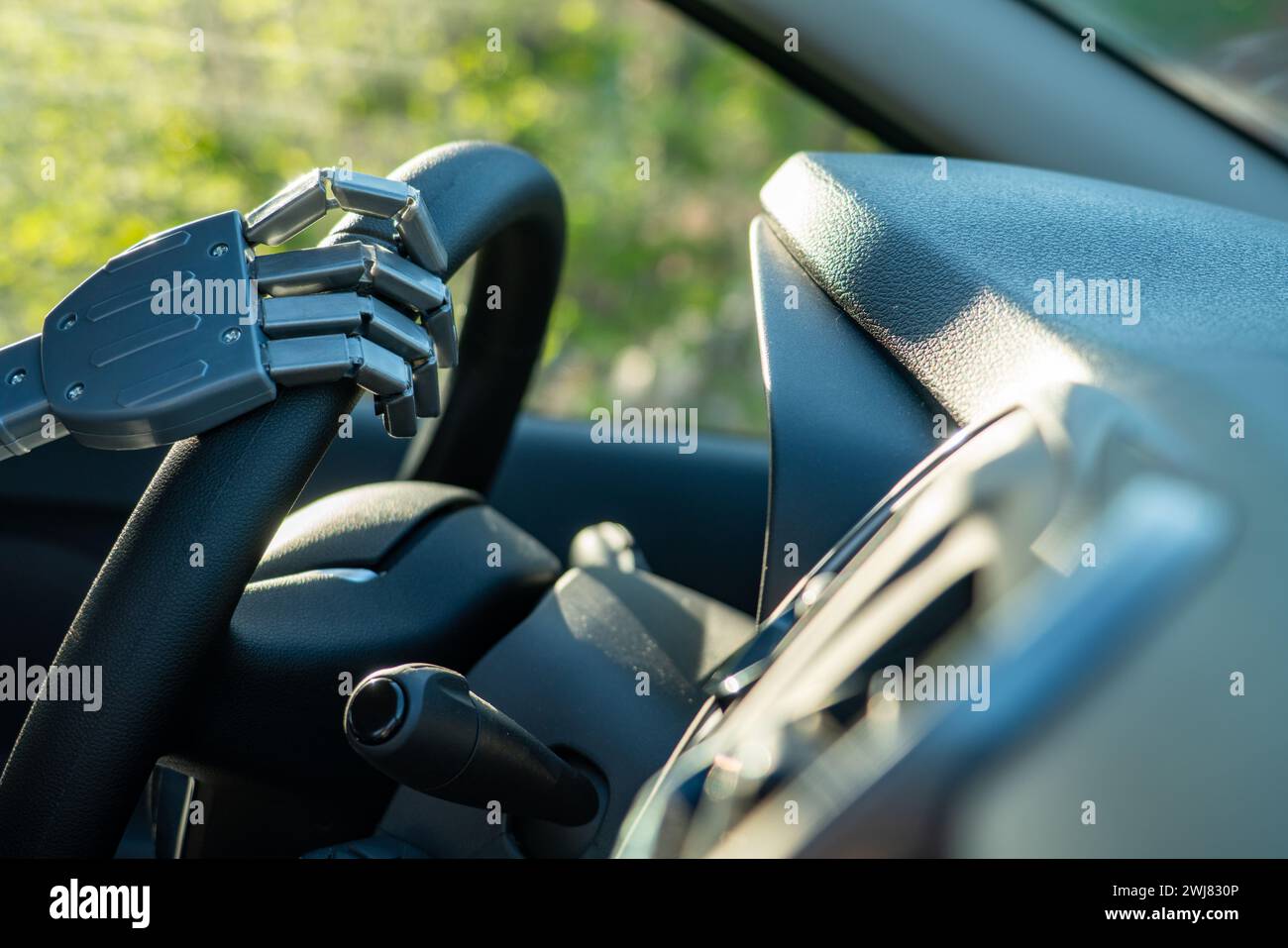 Robot arm on a steering wheel. Artificial intelligence drives a car ...
