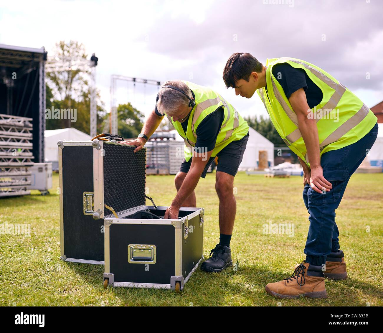 Male Production Team Unpacking Flight Case And Setting Up Outdoor Stage ...