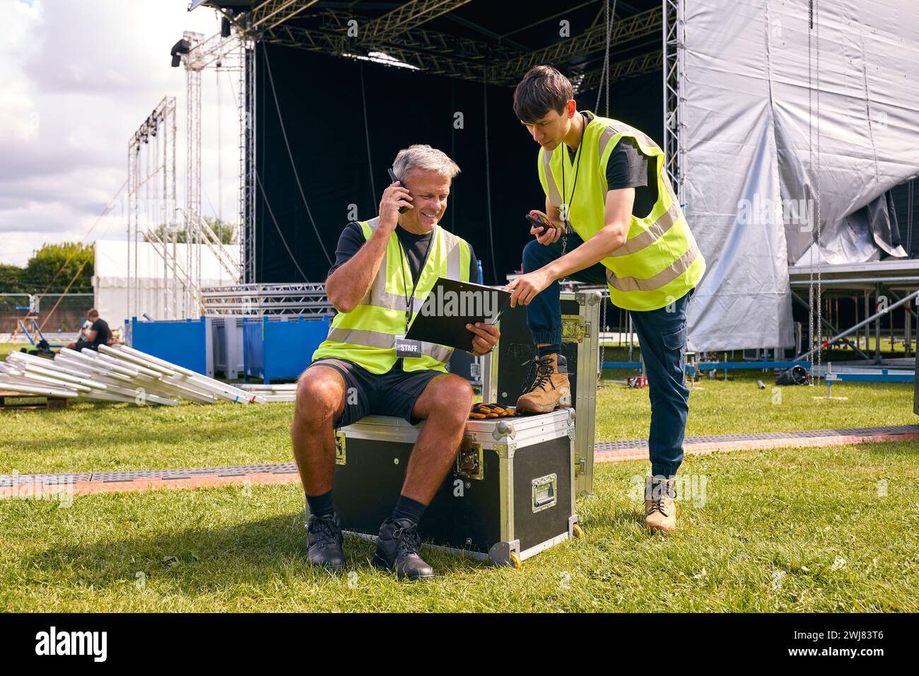 Production Team Talking On Radios And Setting Up Outdoor Stage For ...