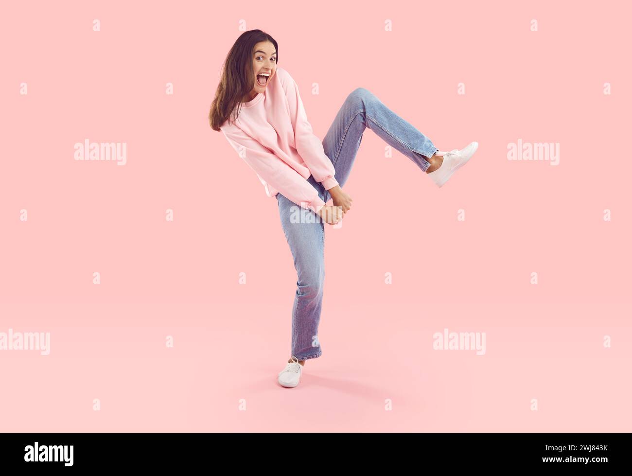 Cheerful young woman dancing standing on one leg Stock Photo - Alamy