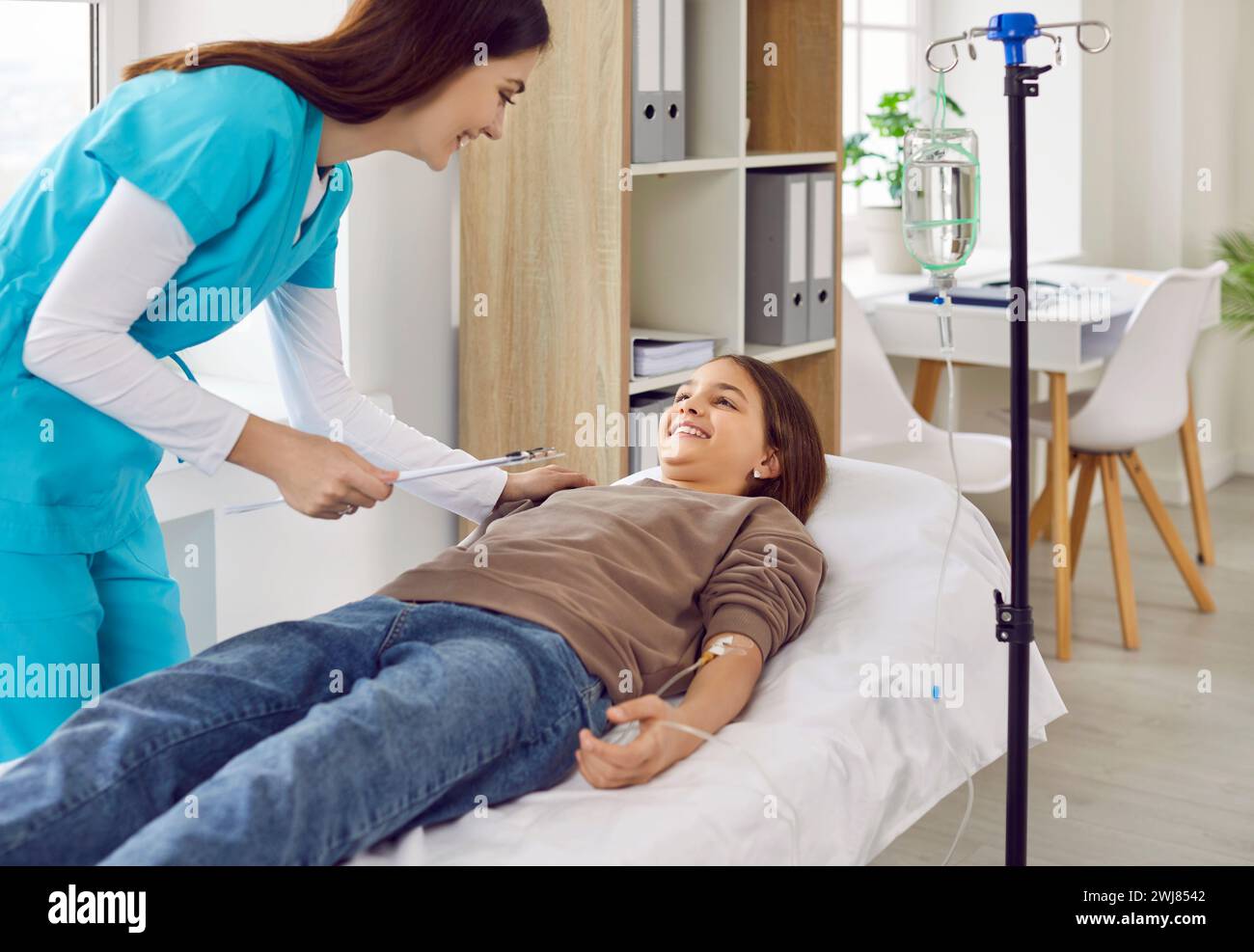 Teenage child girl lying on couch in clinic while receiving IV drip ...