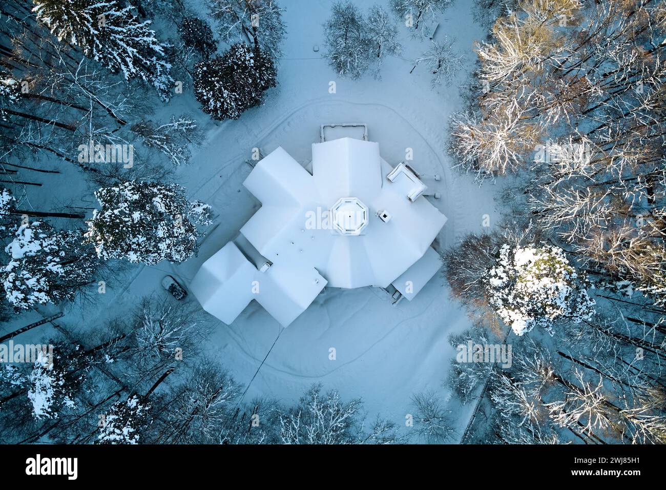 Snow-covered roof of a manor house surrounded by forest, aerial view ...