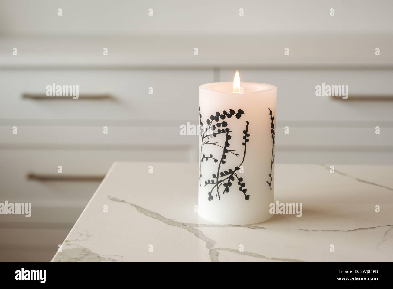White and black candle with burning flame on a kitchen counter Stock ...