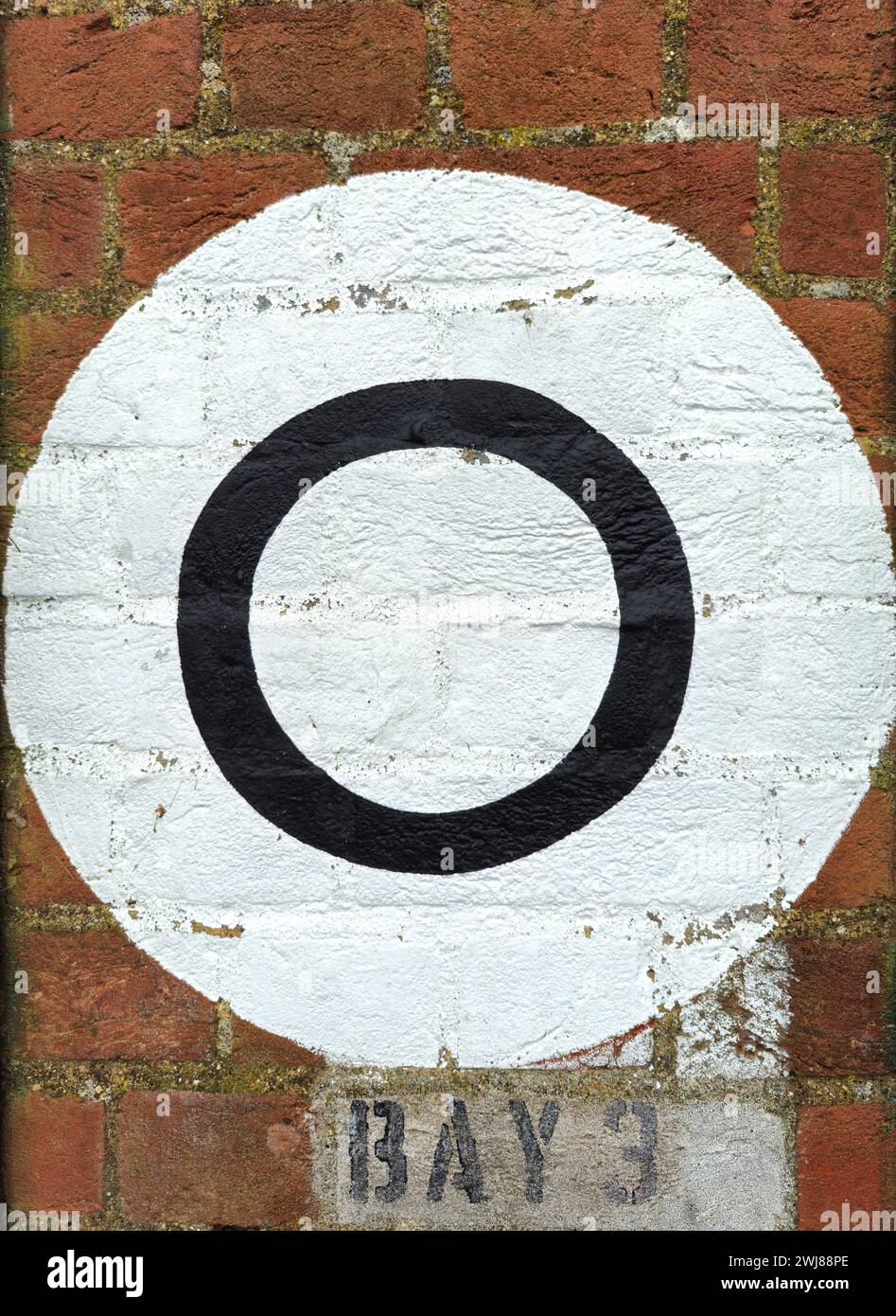 Letter O in black painted on a white circle on a brick wall Stock Photo ...