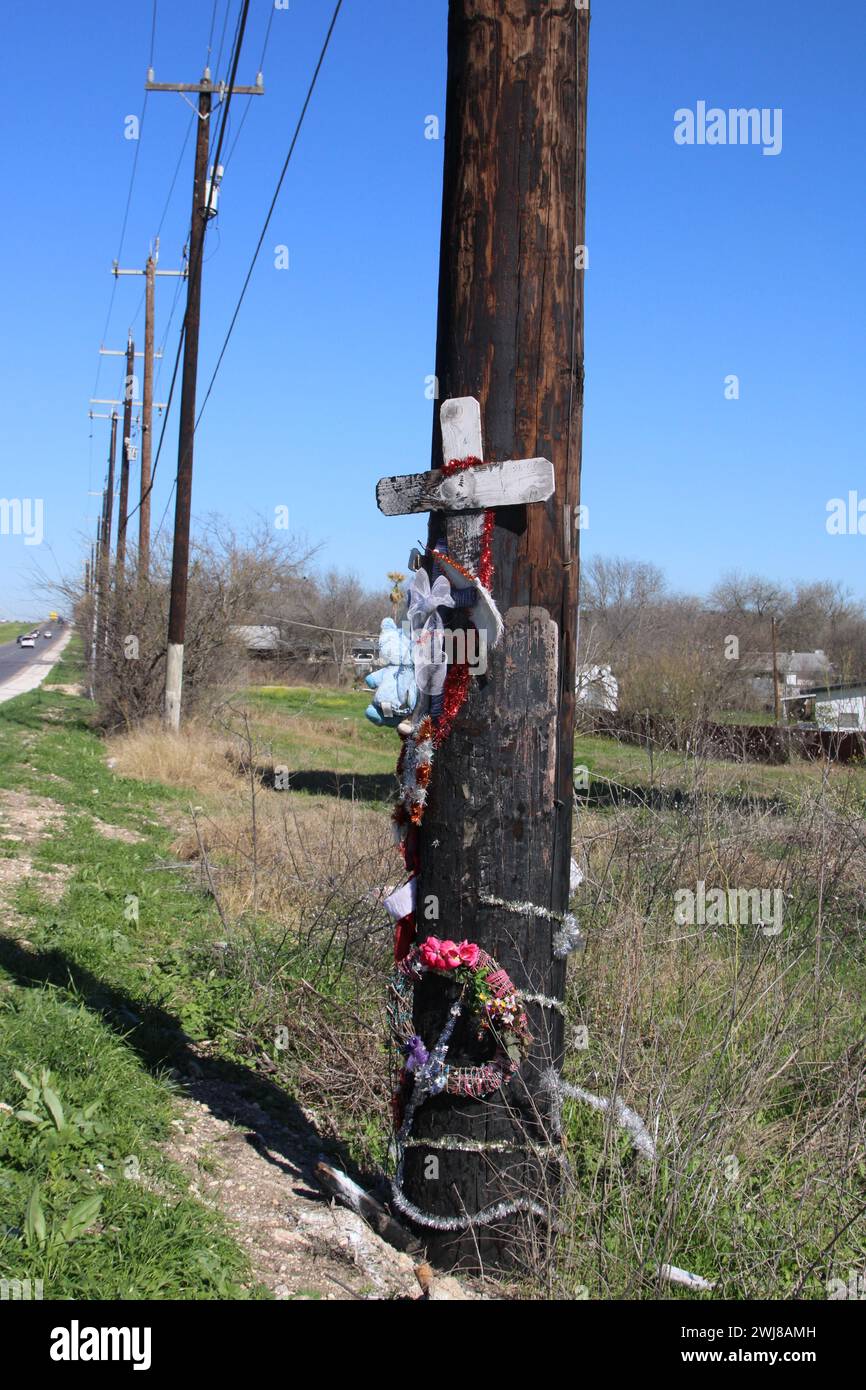 A cross and wreath is attached to a telephone utility pole as part of a ...
