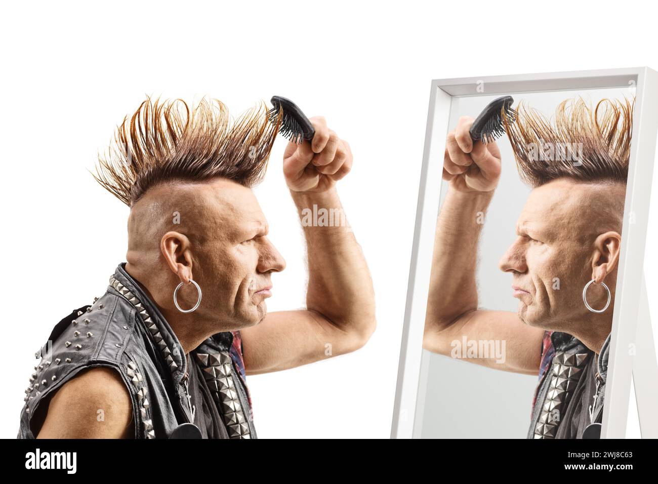 Man combing his mohawk hairstyle with a brush in front of a mirror ...
