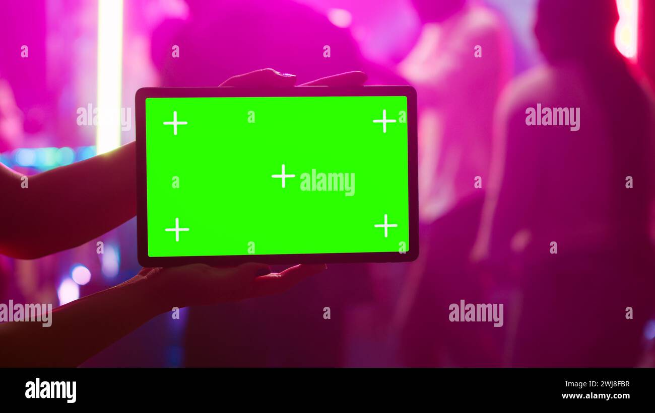 Person showing tablet with greenscreen at nightclub, being on the dance ...