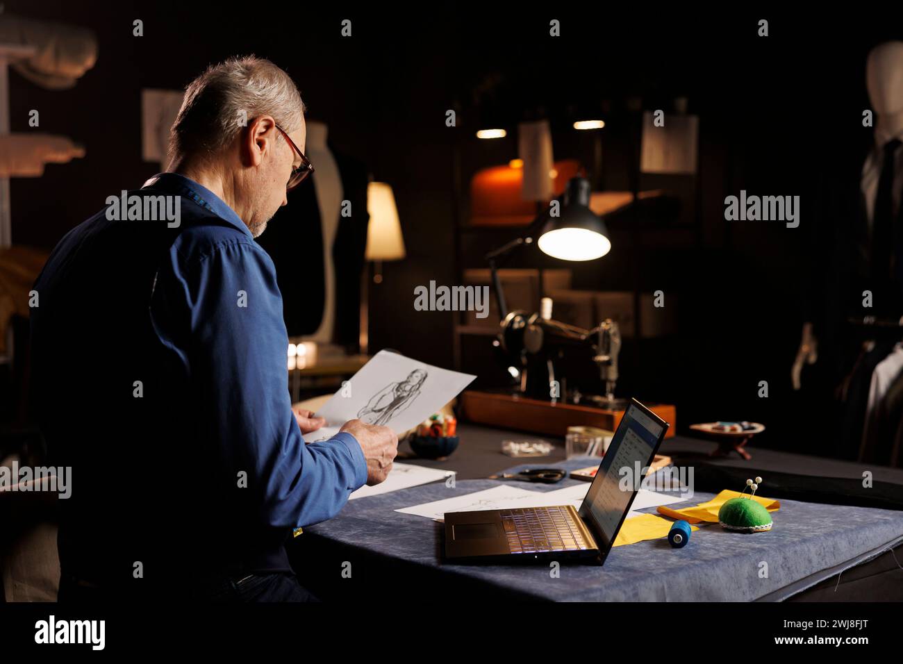 Experienced suitmaker checking tailoring materials price list before ...