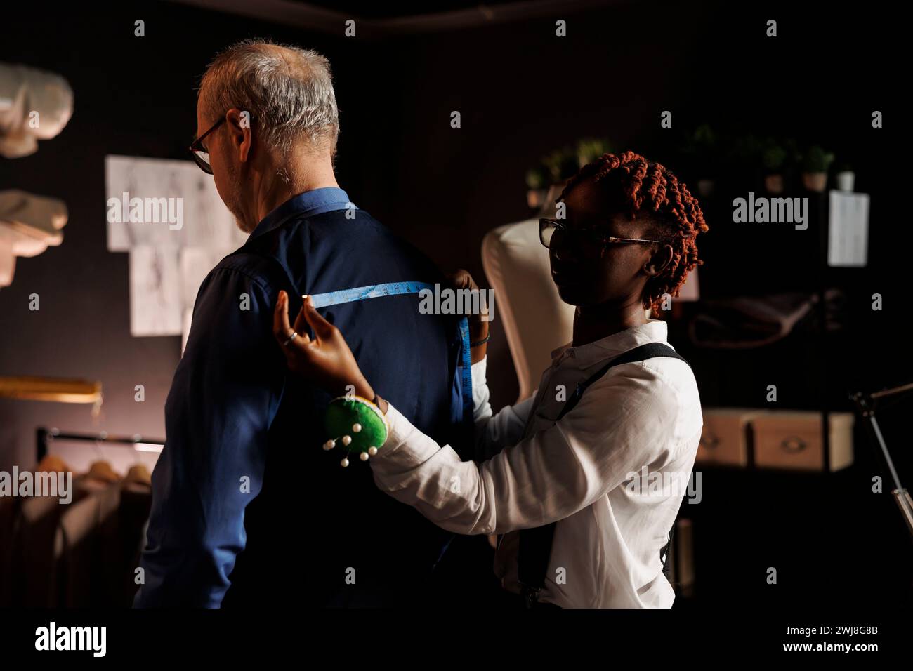 Senior gentleman getting back measurements taken by precise seamstress ...