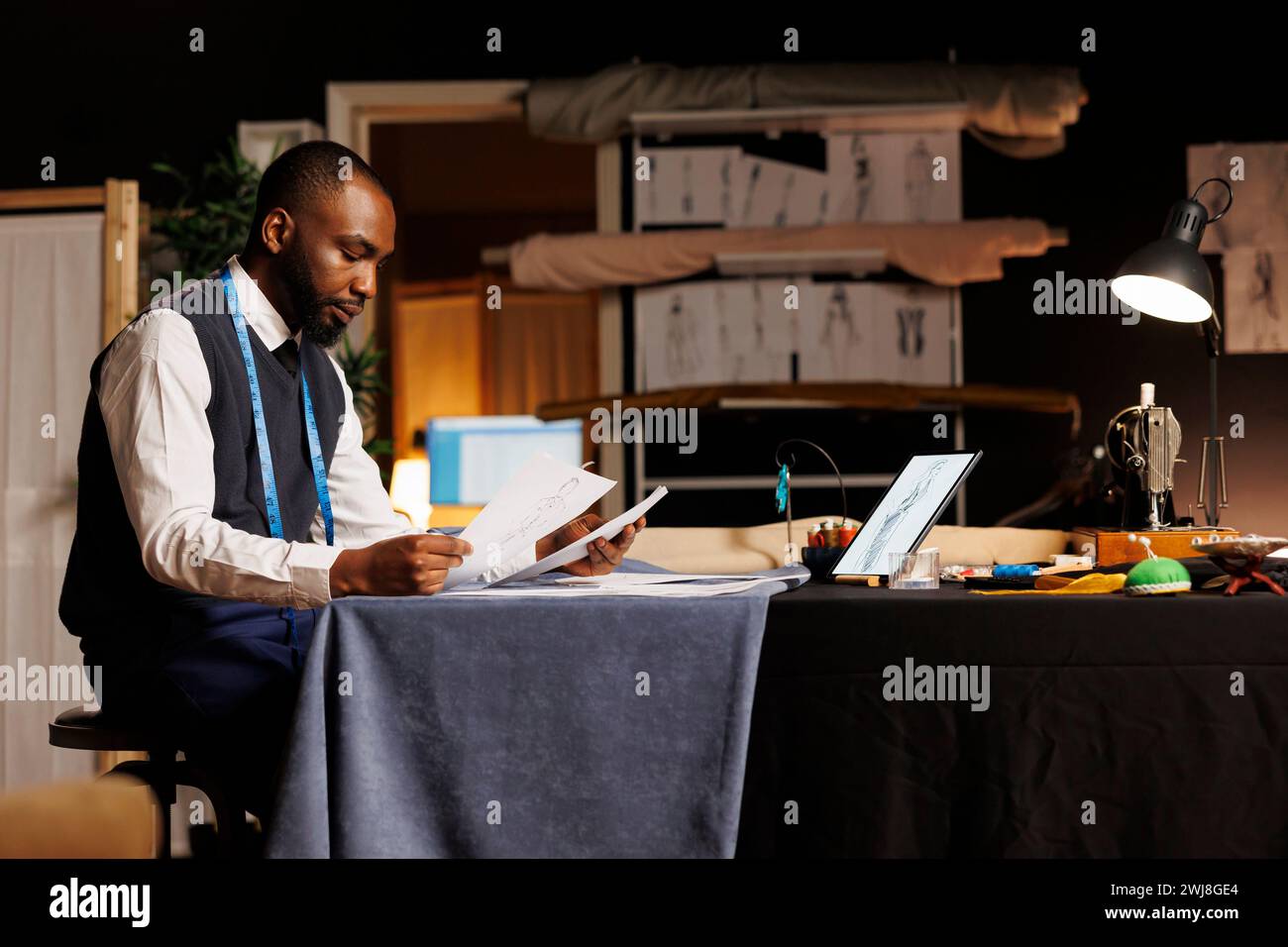 Couturer looking over sketch drawings, trying to pick best design for ...