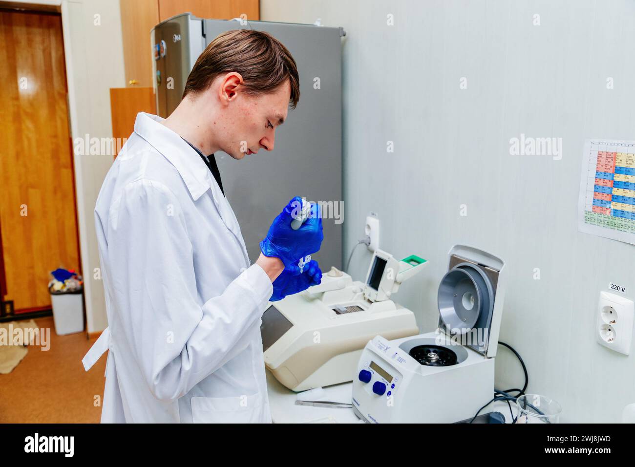 Scientist with gloved hand putting DNA sample into real-time PCR-cycler ...