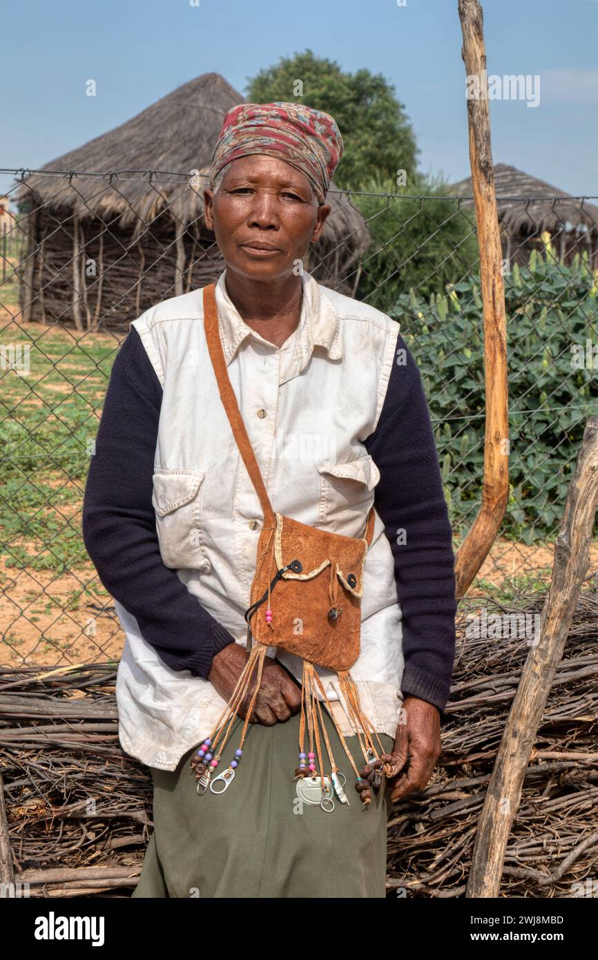 senior african woman in the village, standing in the yard wearing a ...