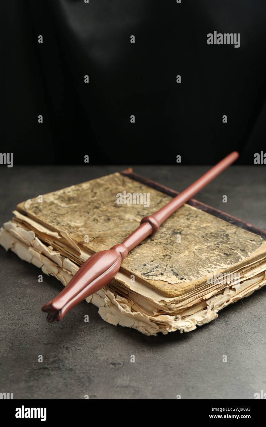 Magic wand and old book on light grey table Stock Photo - Alamy