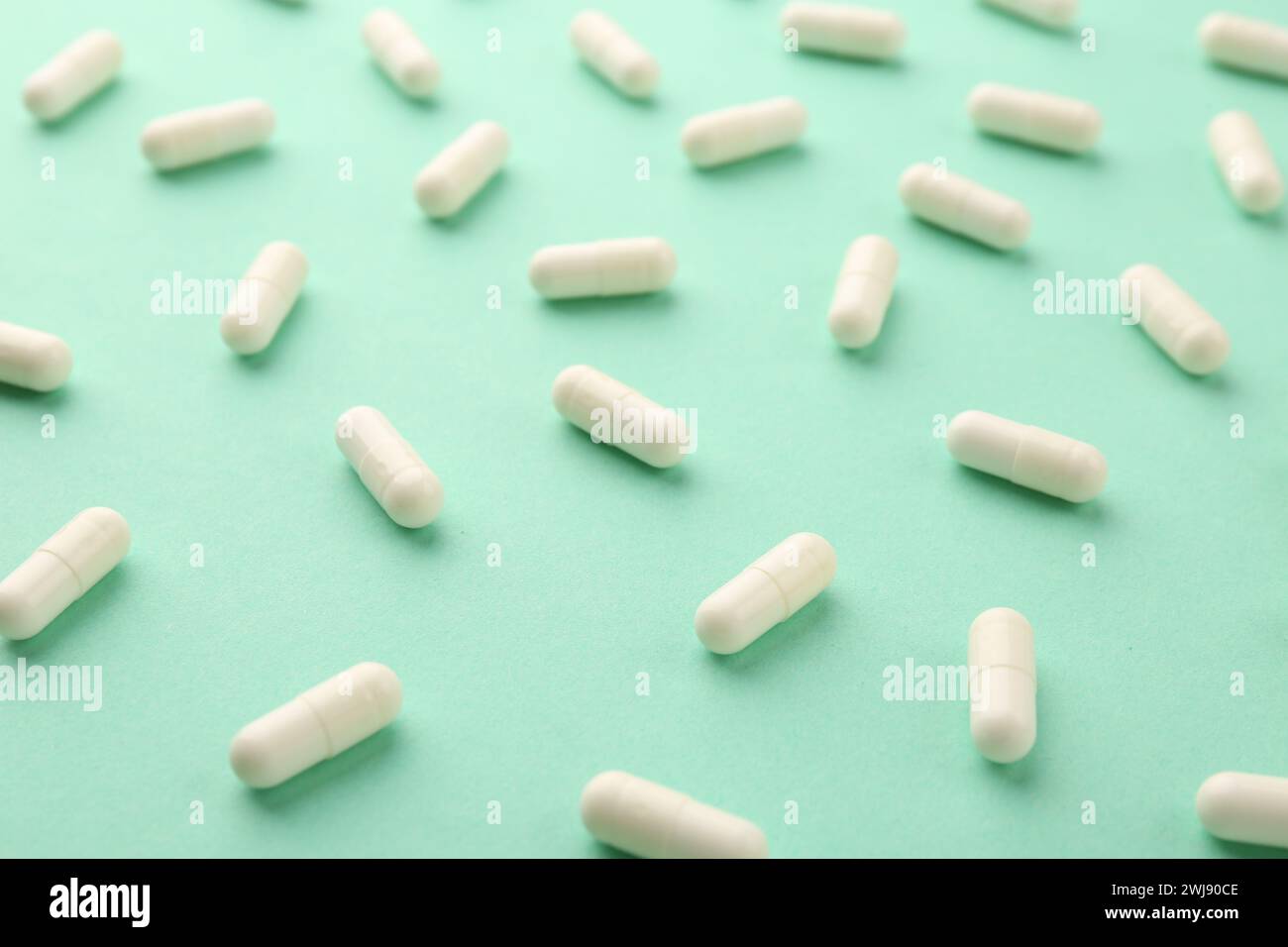 Many vitamin capsules on turquoise background, closeup Stock Photo - Alamy