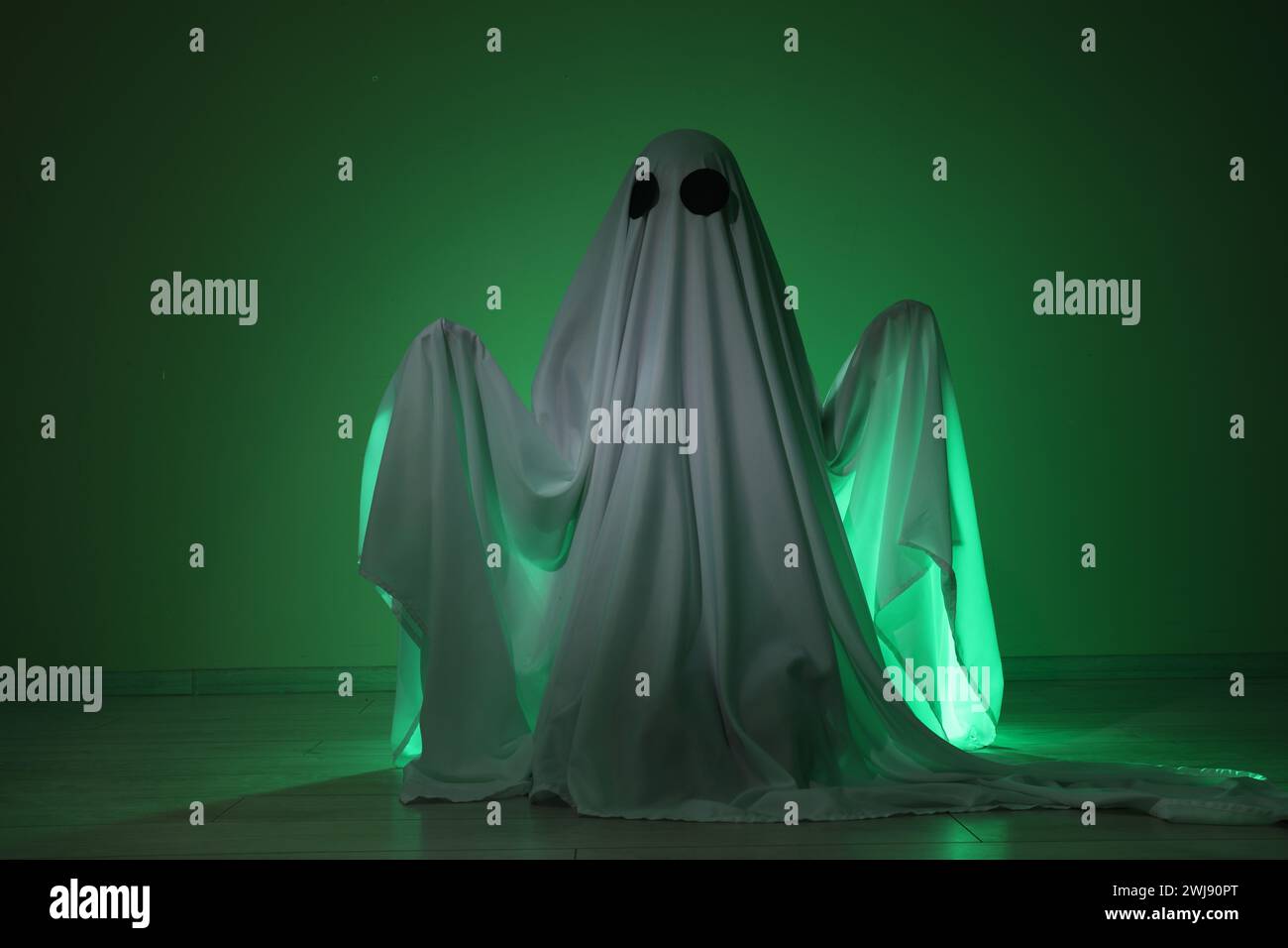 Creepy ghost. Woman covered with sheet in green light Stock Photo - Alamy