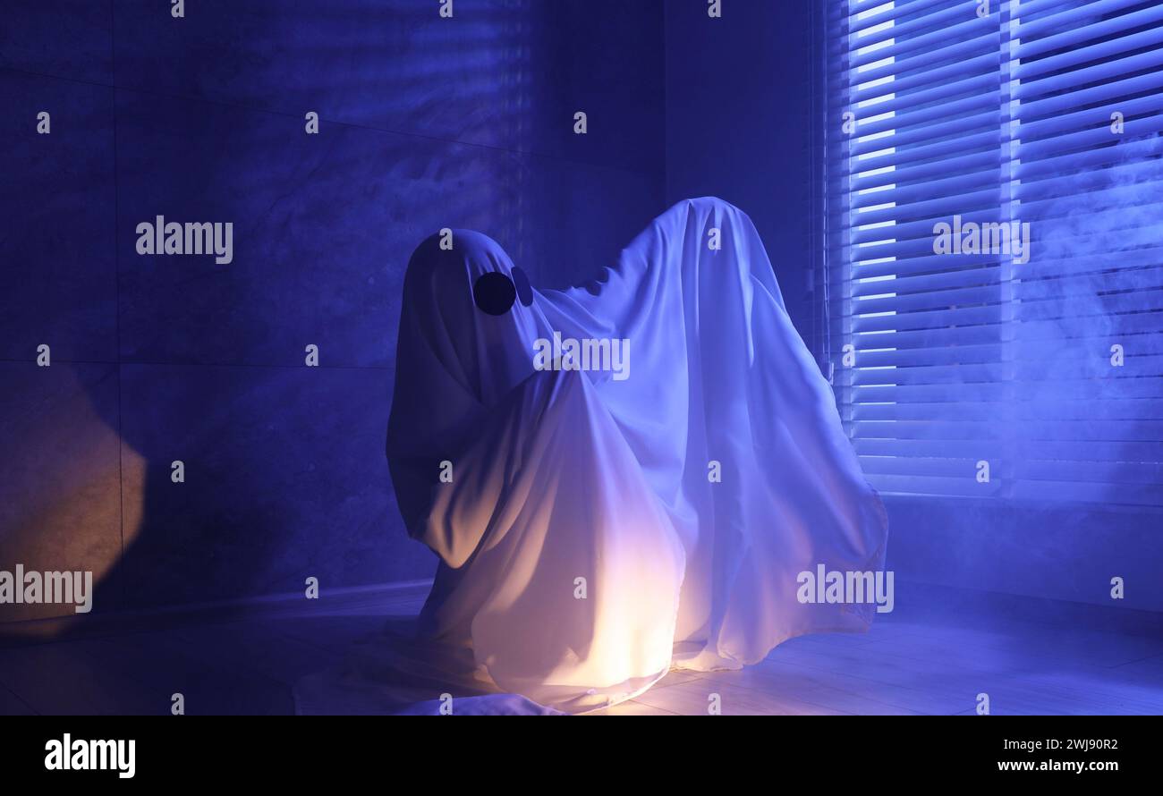 Creepy ghost. Woman covered with sheet near window in blue light Stock ...