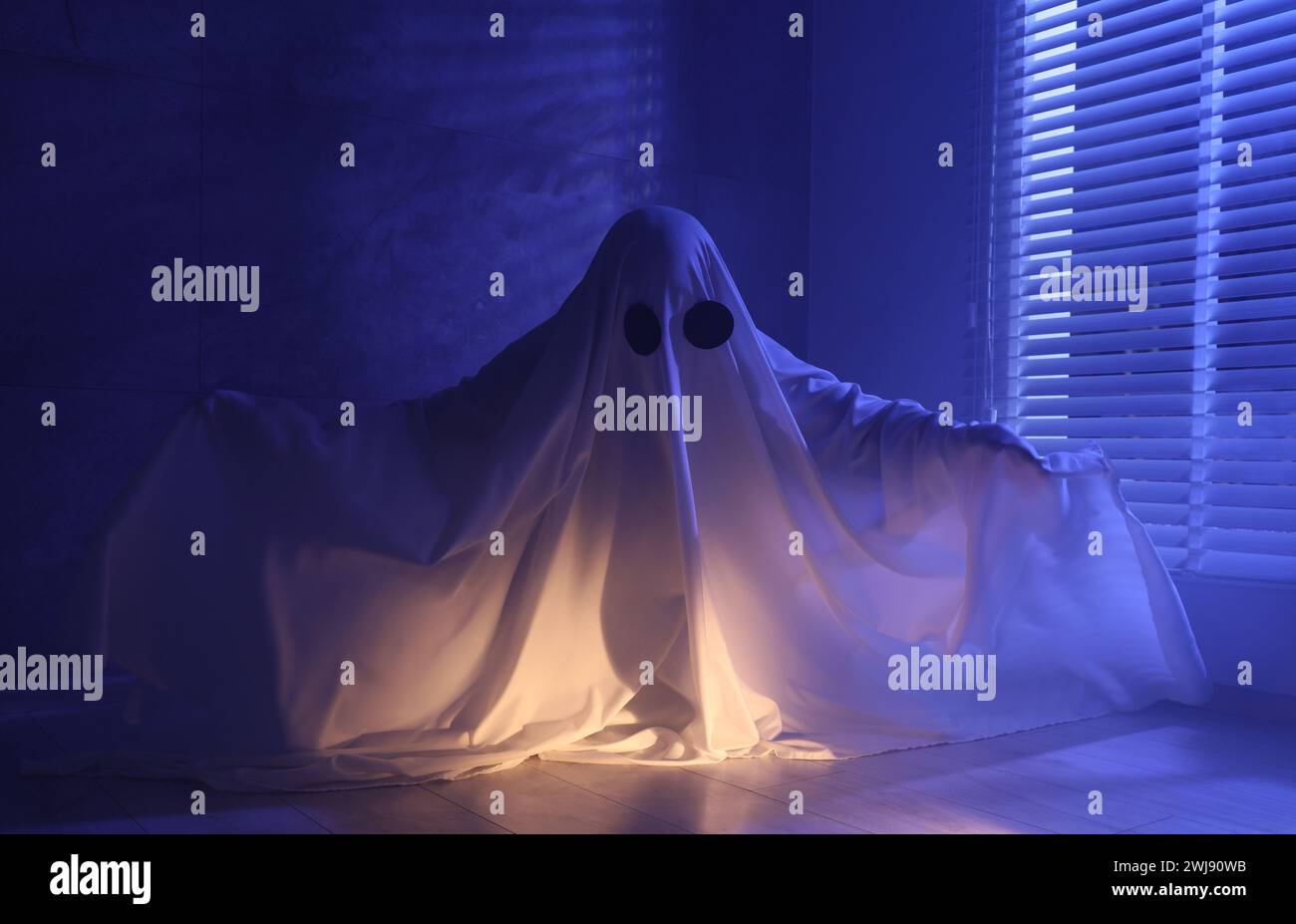 Creepy ghost. Woman covered with sheet near window in blue light Stock ...