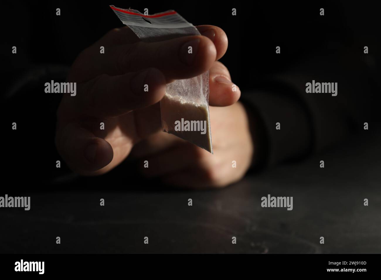 Drug addiction. Man with plastic bag of cocaine at grey table ...