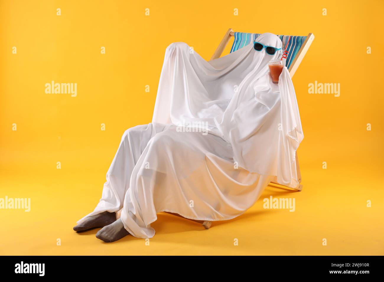 Person in ghost costume and sunglasses with glass of drink relaxing on ...