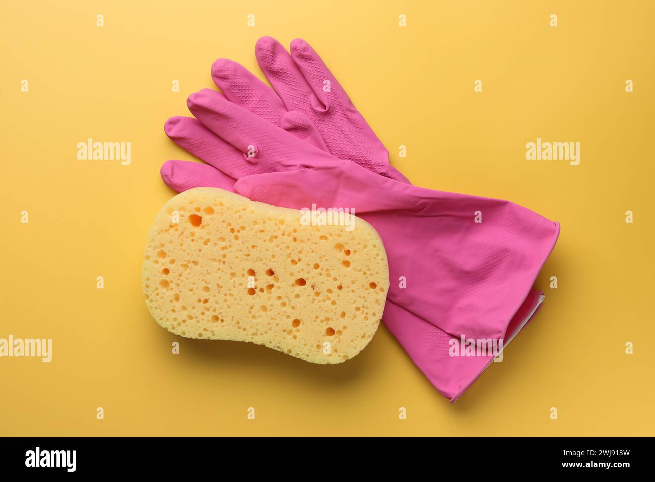Sponge and gloves on yellow background, top view Stock Photo - Alamy