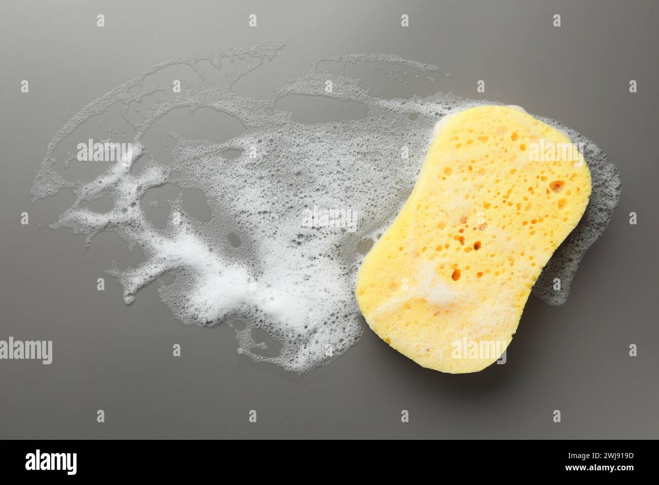 Yellow sponge with foam on grey background, top view Stock Photo - Alamy