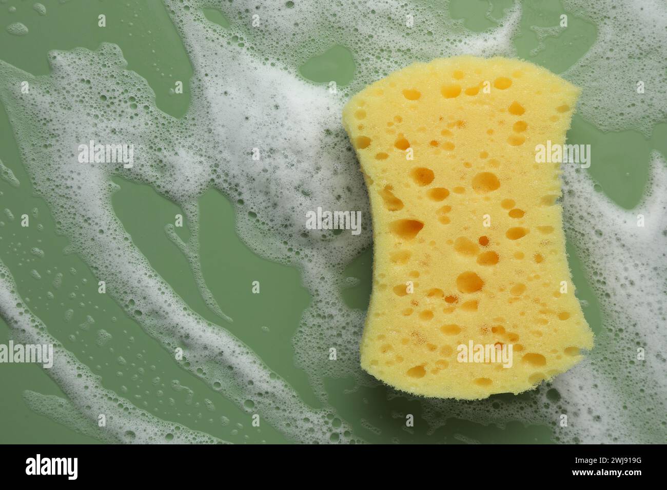 Yellow sponge with foam on green background, top view Stock Photo - Alamy
