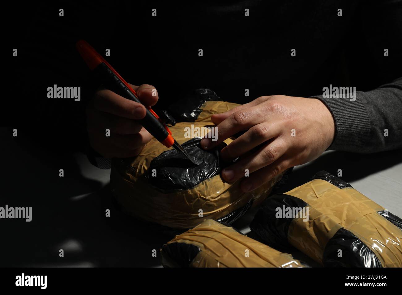 Smuggling and drug trafficking. Man opening package of narcotics with ...