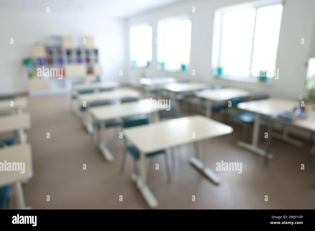 Blurred view of empty school classroom with desks, windows and chairs ...