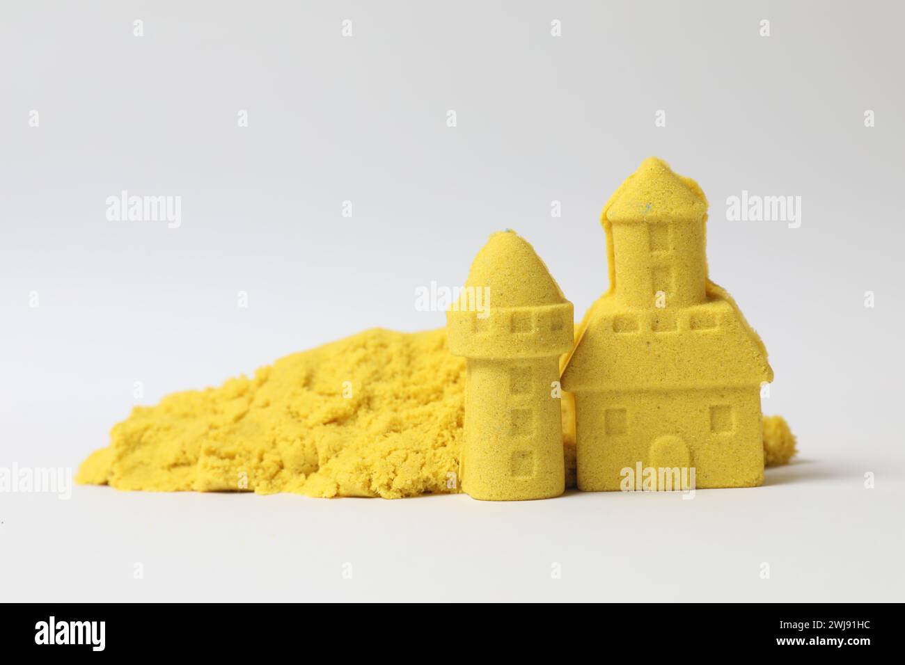 Castle and tower made of yellow kinetic sand on white background Stock ...