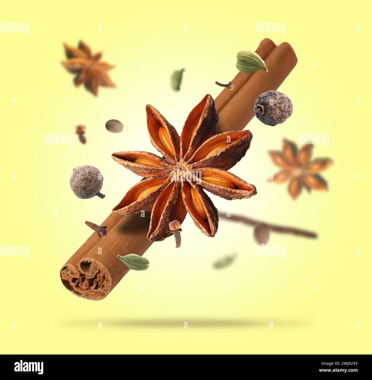 Different aromatic spices falling on yellow background Stock Photo - Alamy