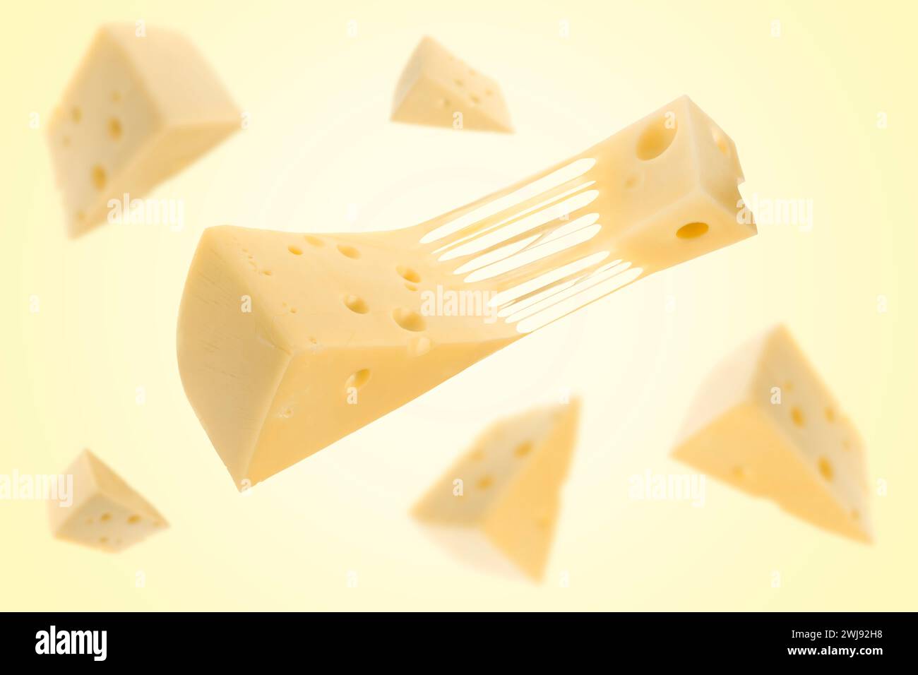Pieces of cheese falling on yellow background Stock Photo - Alamy