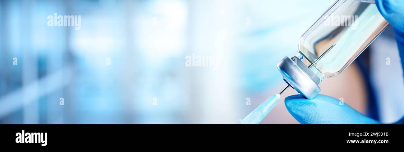Doctor filling syringe with medication from glass vial on blurred ...
