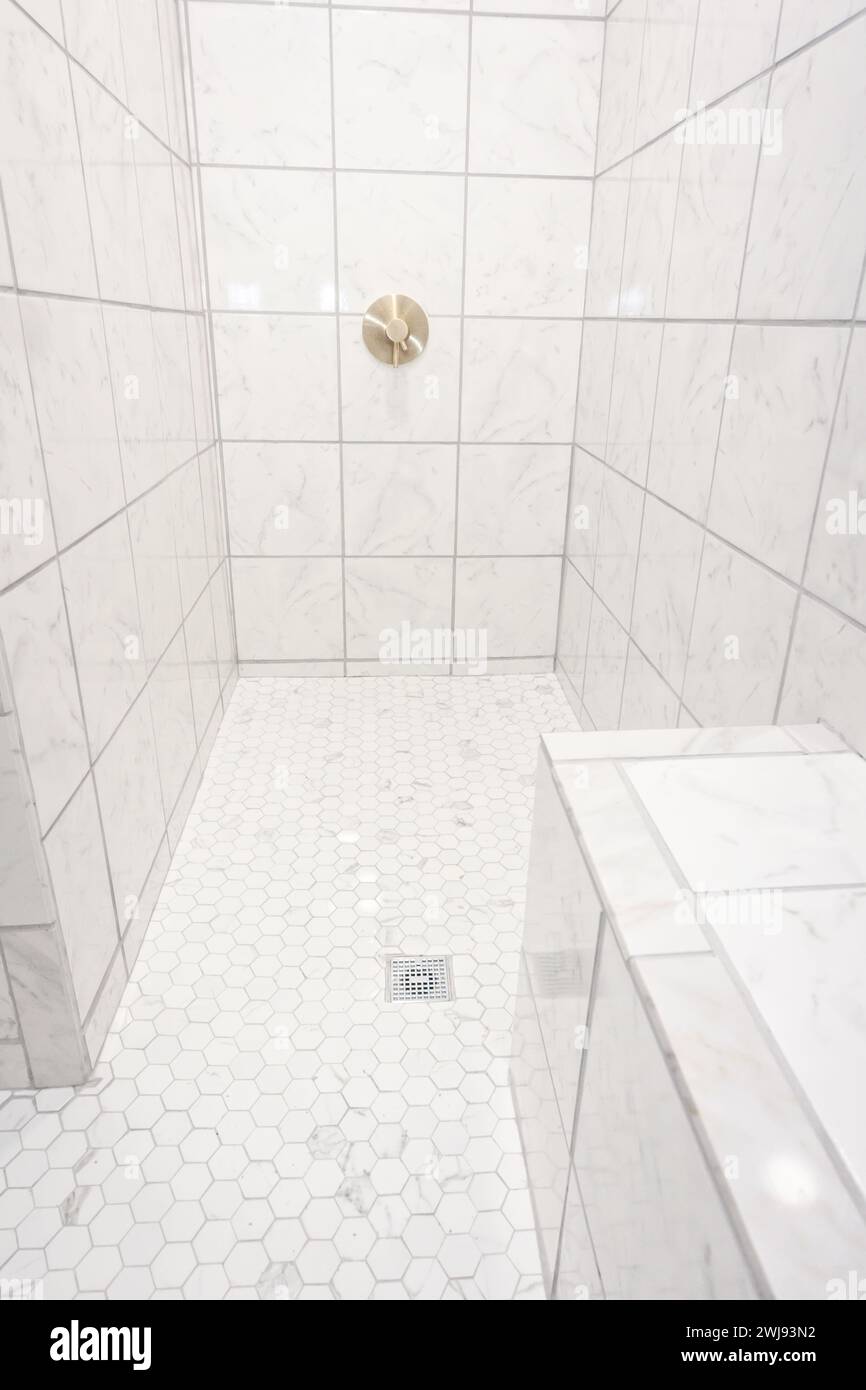 White and gray marbled tile large empty recently renovated home shower in a master bathroom ...