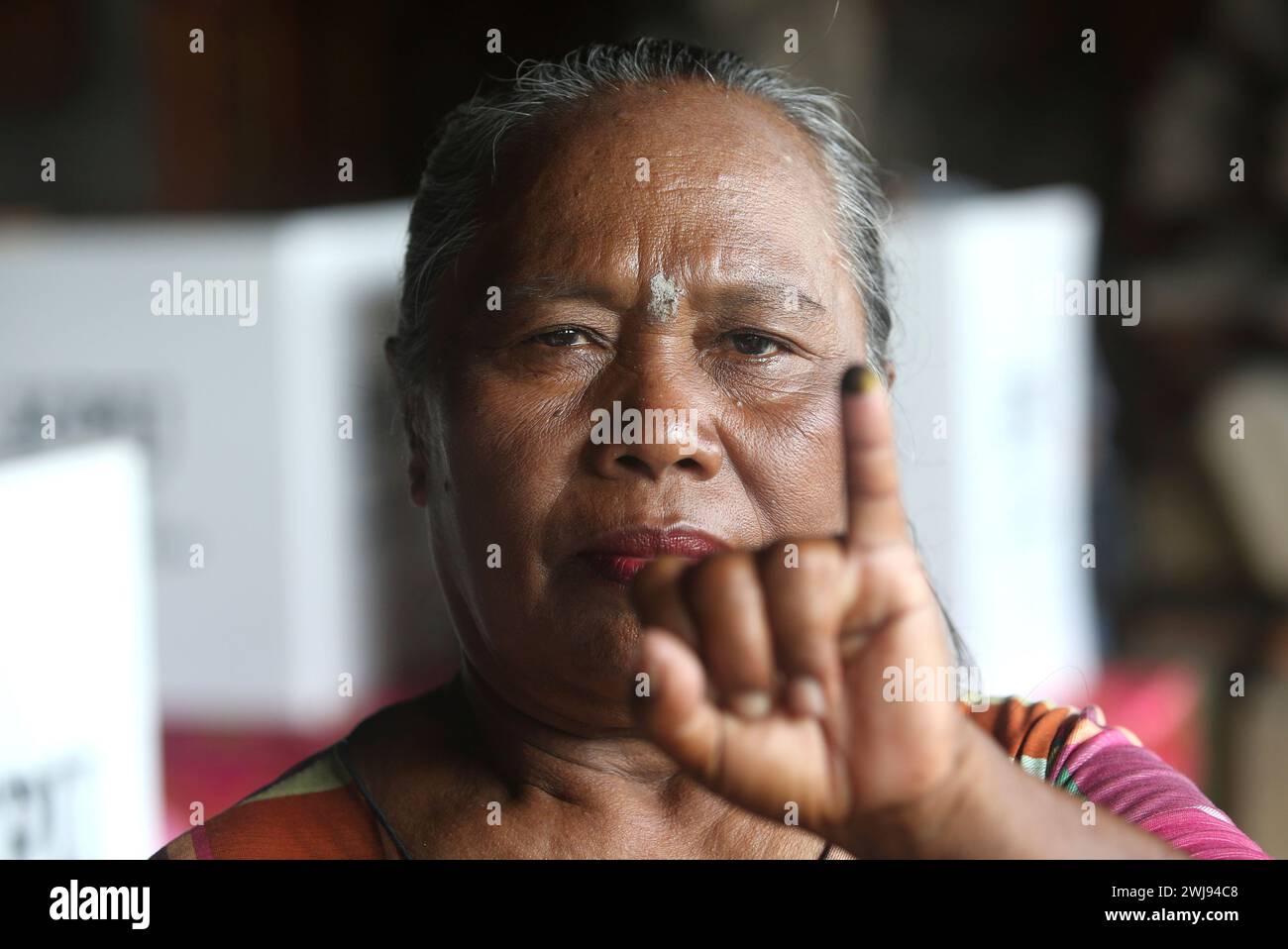 A woman shows her marked finger with ink after casting her ballot at a ...