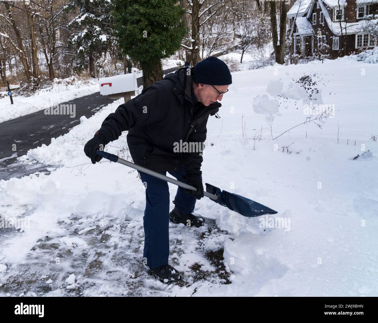 Chappaqua, NY- Feb 13 2024 - A man shovels out his driveway after a ...
