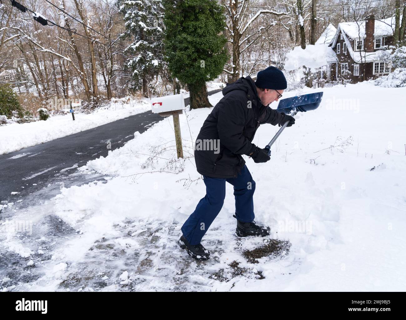Chappaqua, NY- Feb 13 2024 - A man shovels out his driveway after a ...