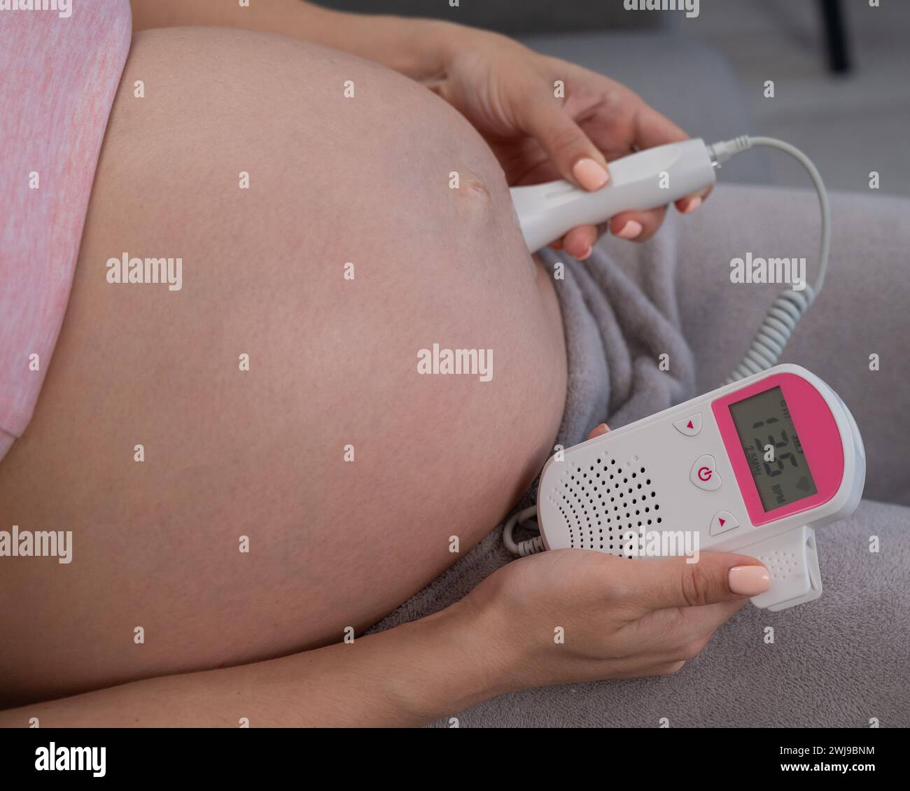 Close-up of a pregnant woman's belly using a home doppler. Normal baby ...