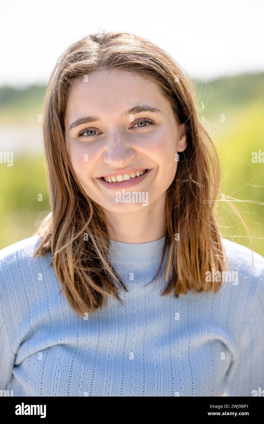 The photograph is a sunlit portrait of a young woman with a bright and ...