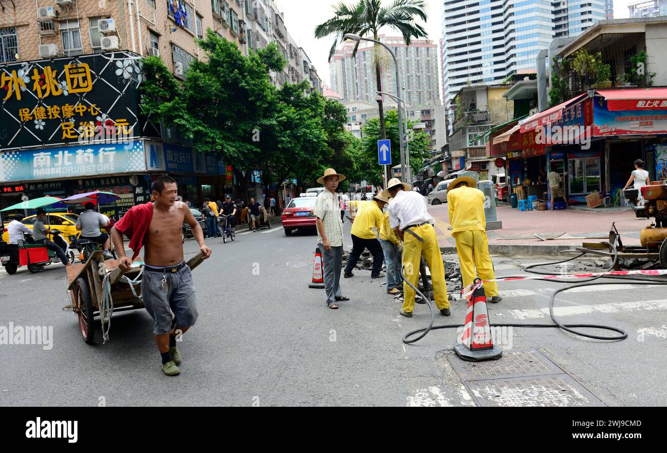 A Chinese man pulling a cart in a small neighborhood in Shenzhen, China ...