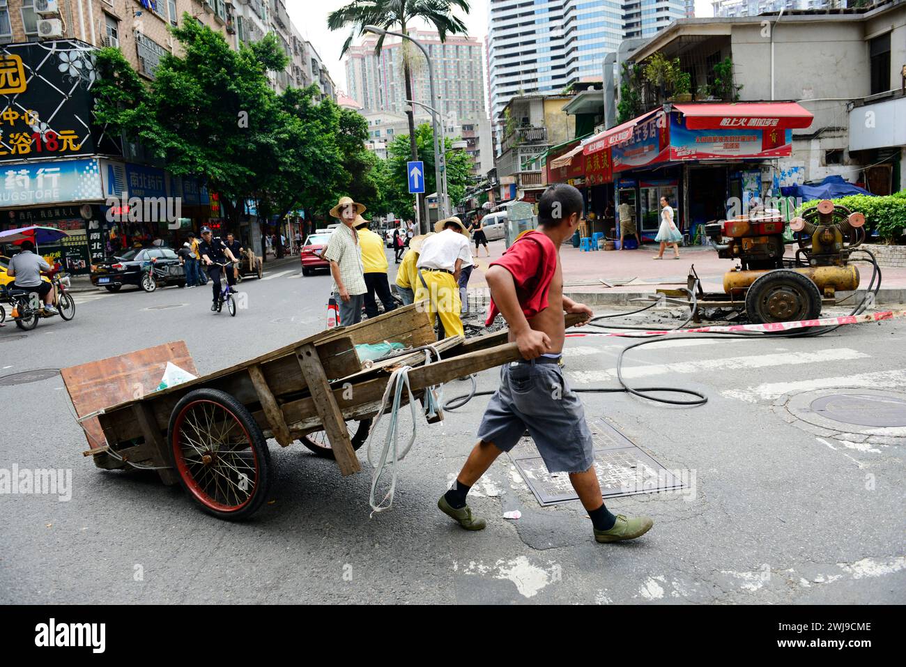 A Chinese man pulling a cart in a small neighborhood in Shenzhen, China ...