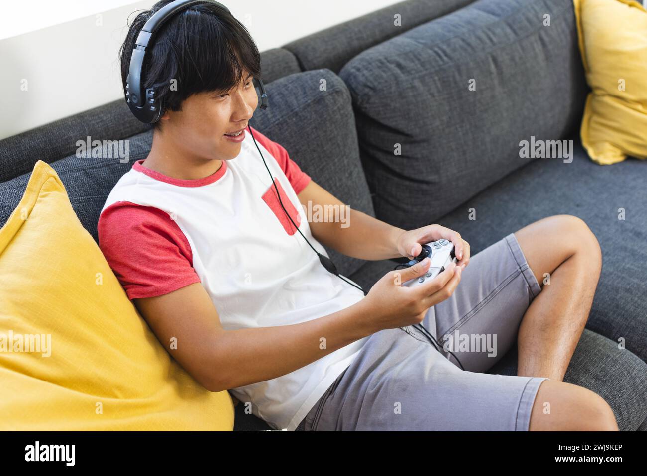 Teenage Asian boy enjoys gaming at home, with copy space Stock Photo ...