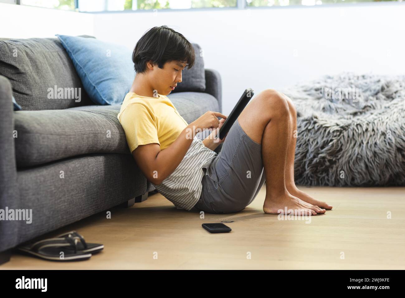 Teenage Asian boy focused on his tablet at home Stock Photo - Alamy