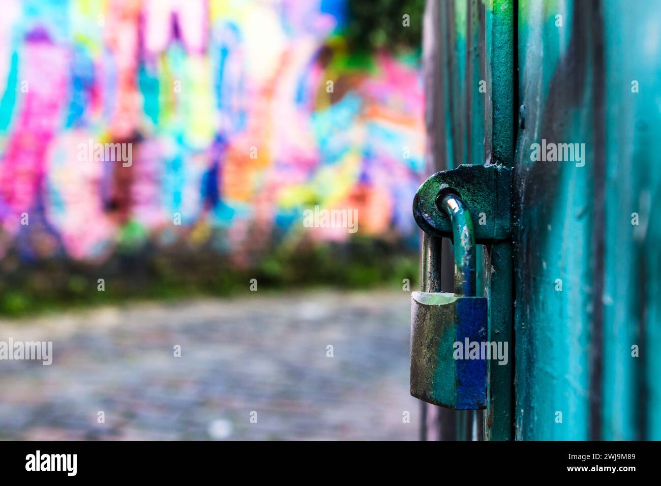 padlock closes a green iron gate with multicolored art concept in ...