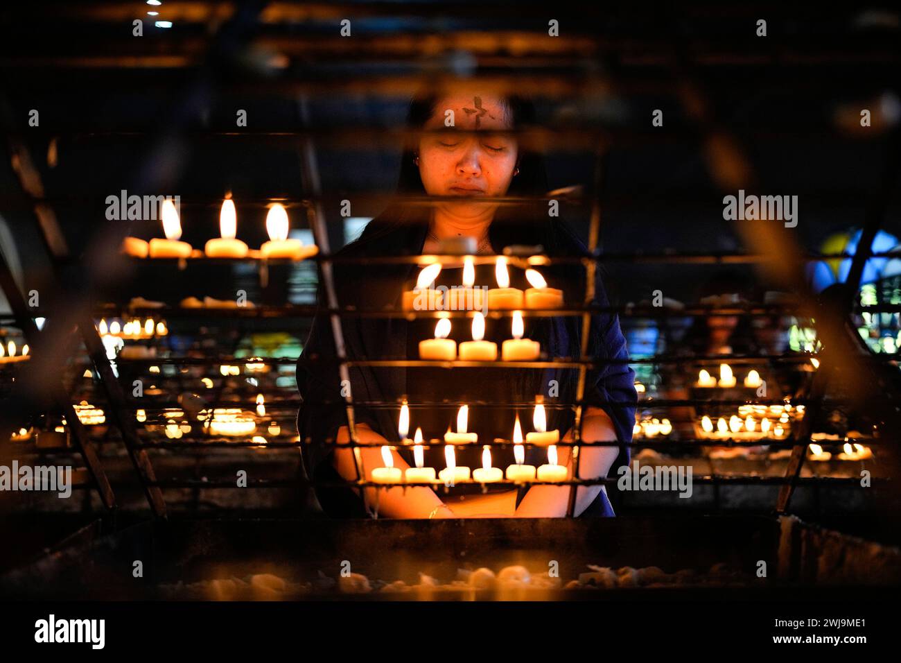 A devotee marked with an ash cross on her forehead prays at the ...