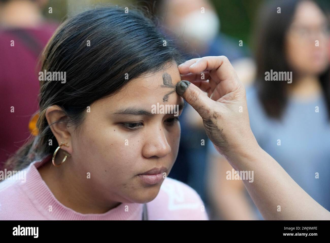 A devotee is marked with an ash cross on her forehead outside the ...