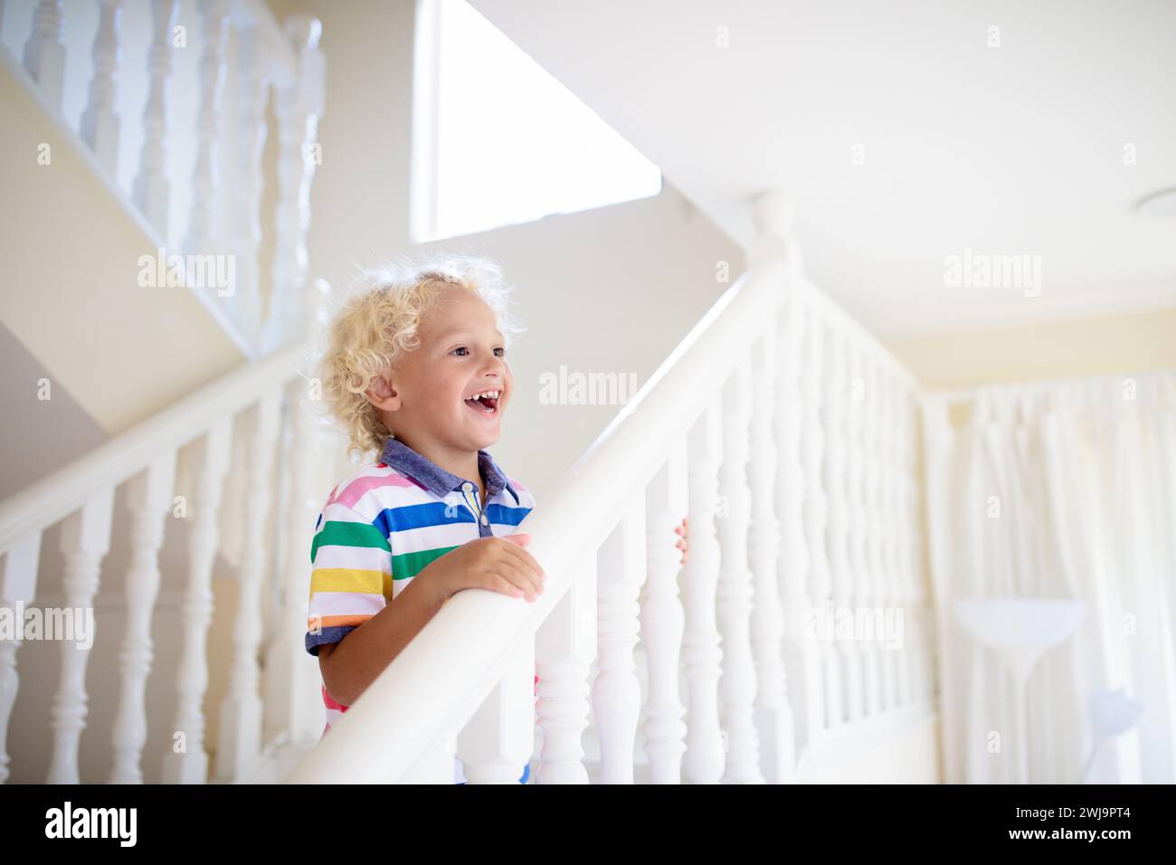 Kid walking stairs in white house. Little boy playing in sunny ...