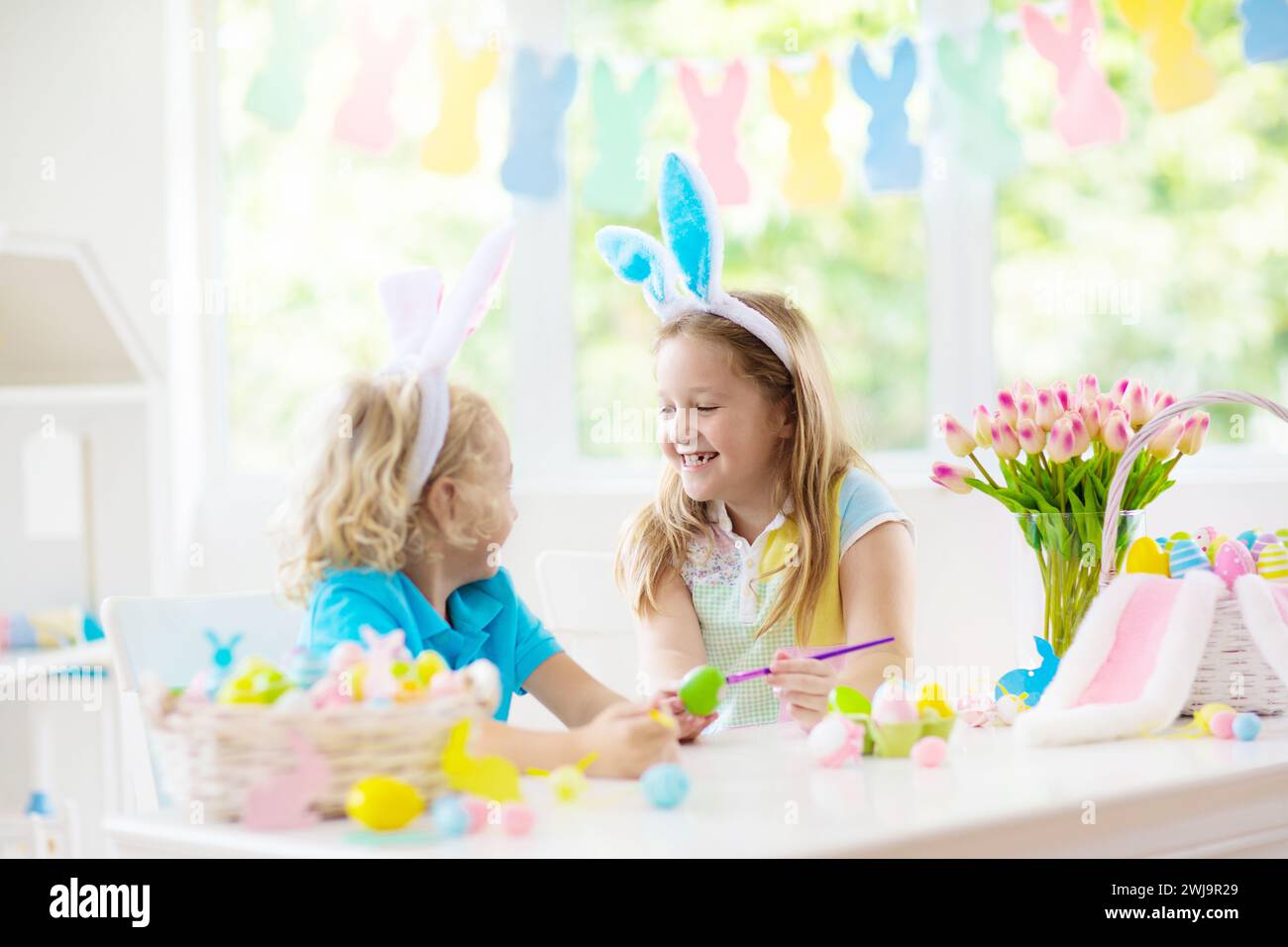 Kids dyeing Easter eggs. Children in bunny ears dye colorful egg for ...